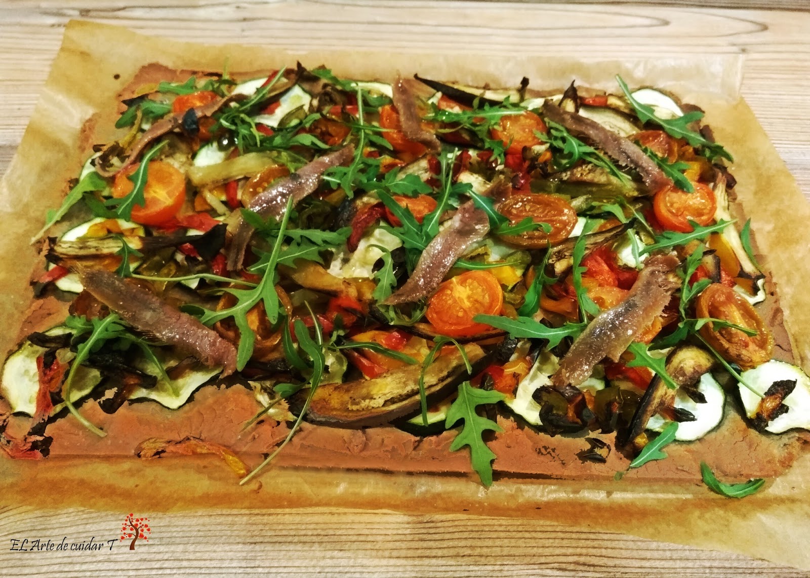 Coca lista para servir con la rúcula, las anchoas y un chorrito de ...