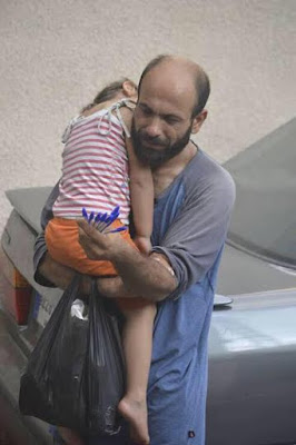 Heartbreaking pics: Syrian father sells pens while carrying his child