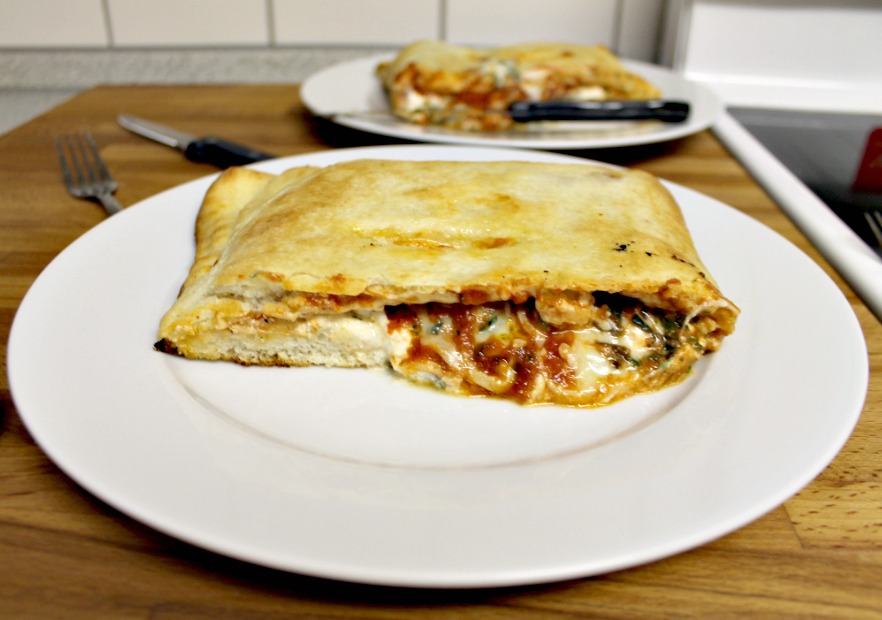 A calzone filled with Ricotta, Mozzarella, Spinach, and Sauce.