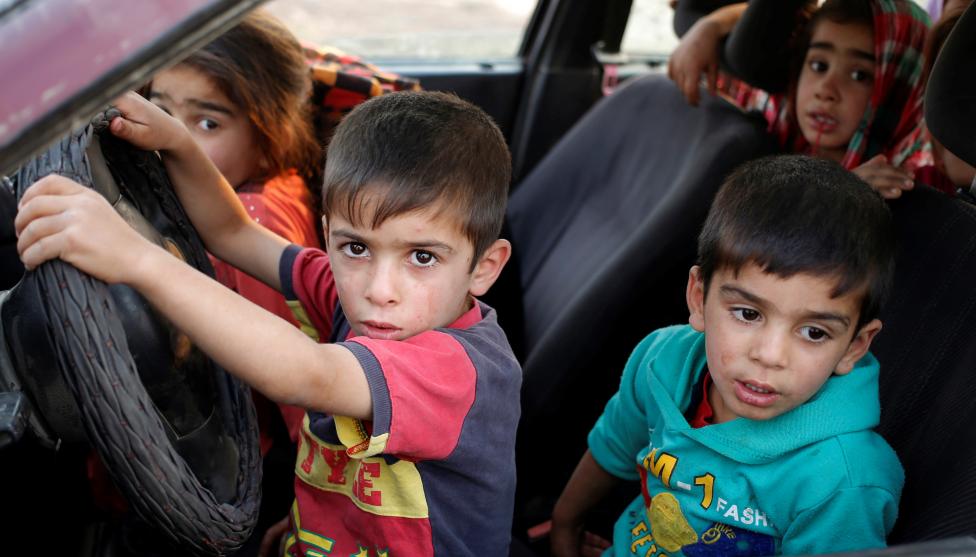 Internally displaced children sit in a car near Mosul, Iraq