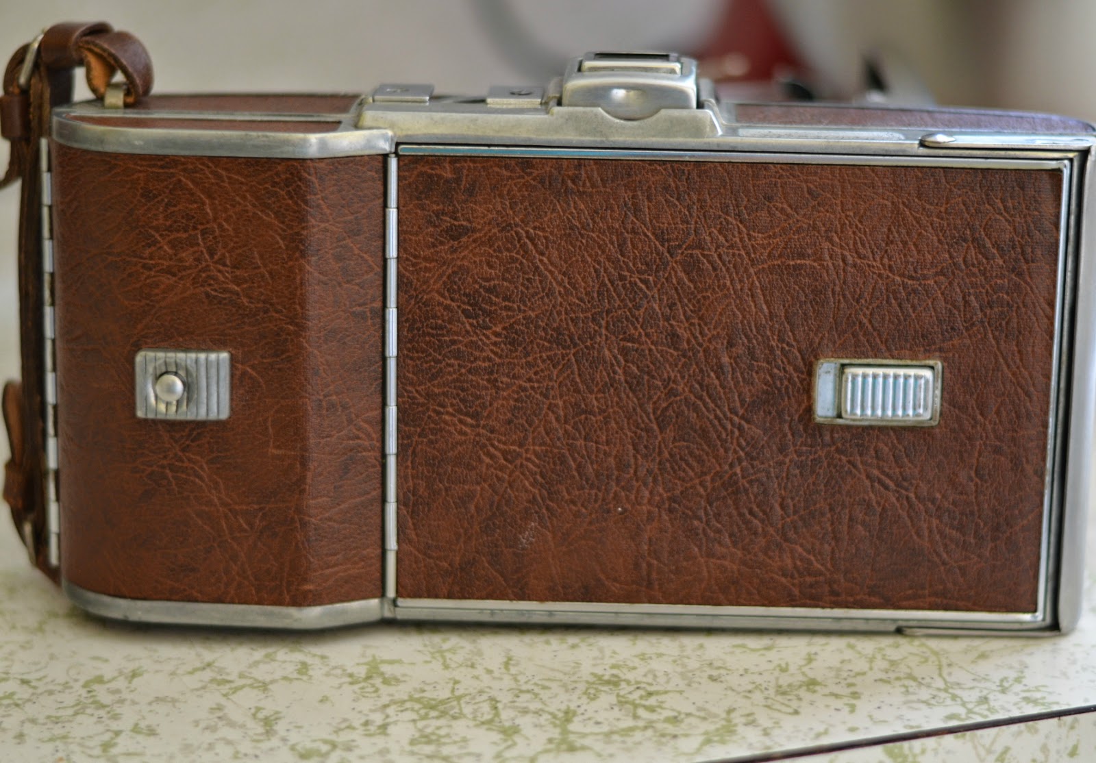 Pressing the long button will open up the first hinged flap of the camera