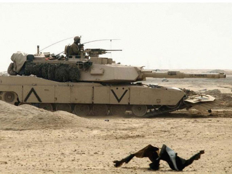 M1A1 Abrams fitted with a mine plow rolls behind a fragment riddled ...