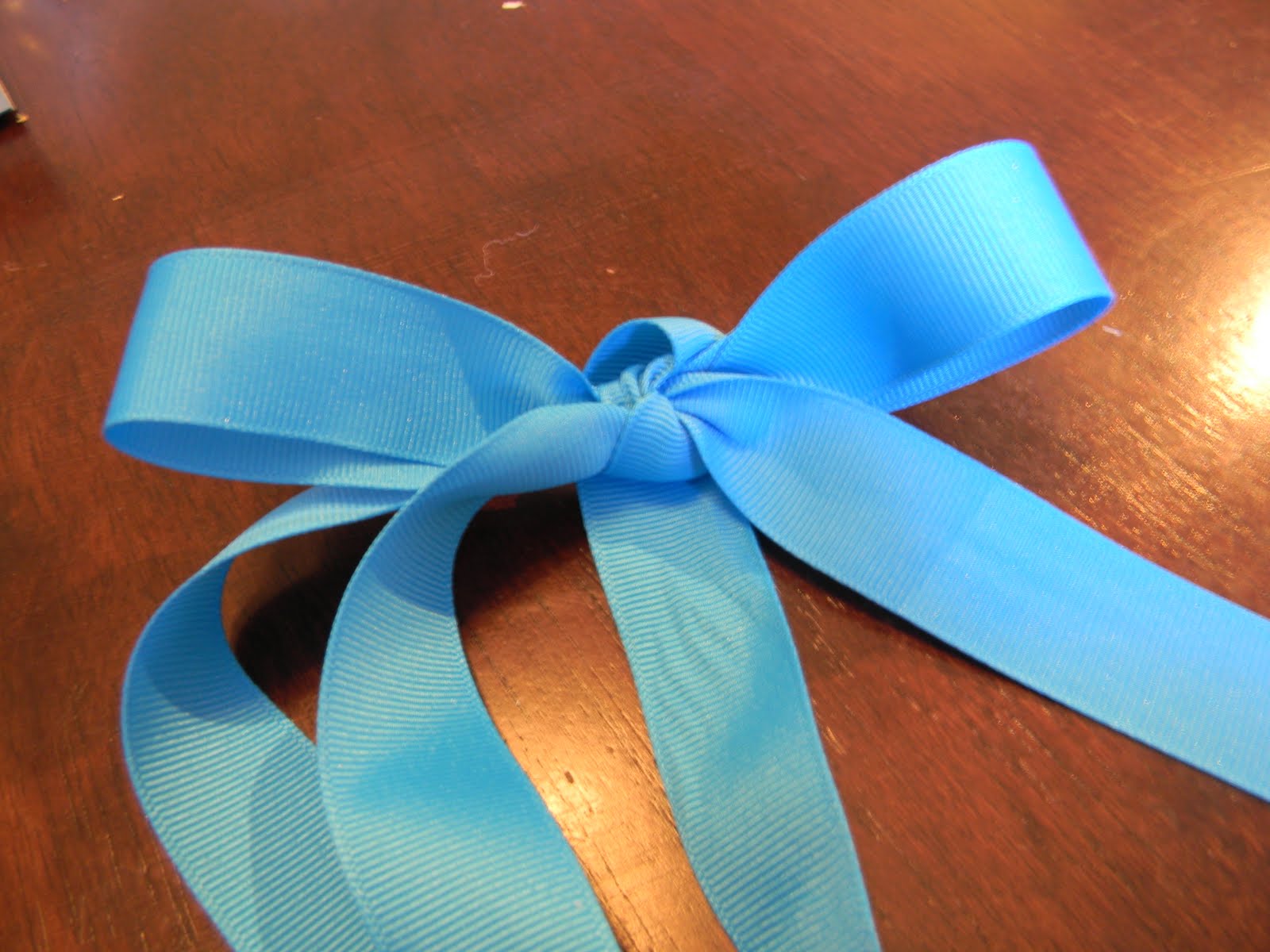 Now, slip the loop of ribbon under the wreathe, with the bow coming up ...